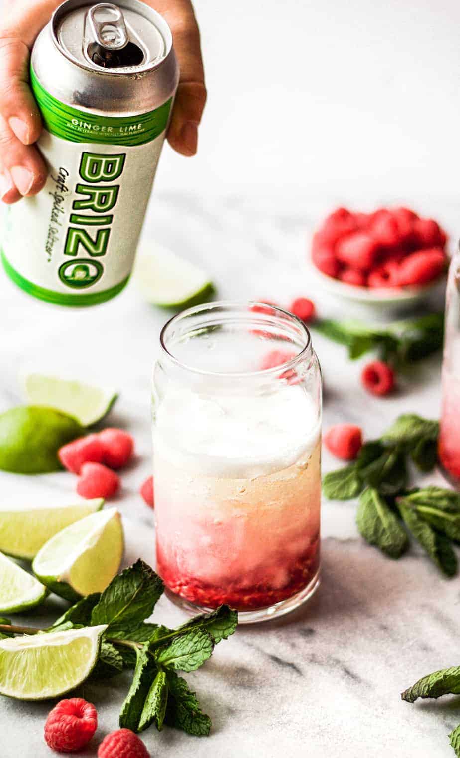 pouring a can of brizo into raspberry gin seltzer drink